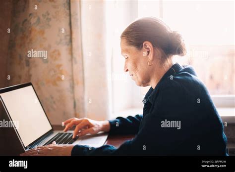 Happy Mature Woman Using Laptop Computer While Working At Home Stock