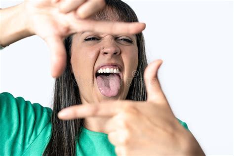 Young Woman Making A Frame With Her Fingers And Sticking Out Her Tongue
