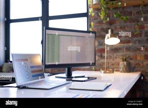 Working On Business Analytics Laptop And Monitor Displaying Data In