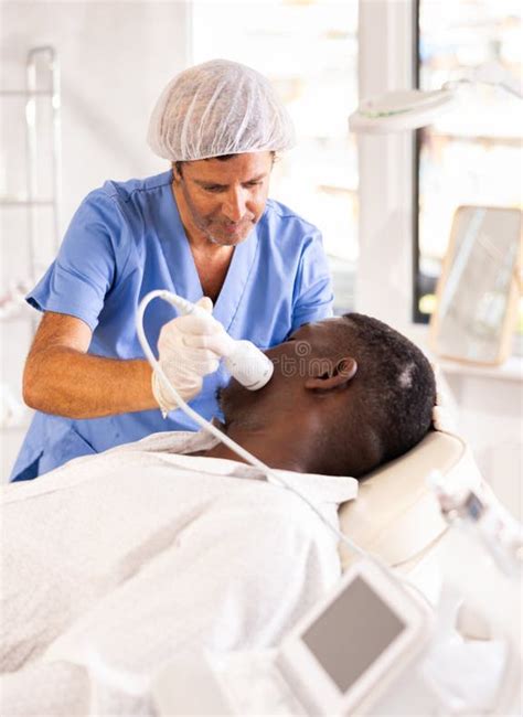 Cosmetologist Performing Facial Cryotherapy Procedure On African