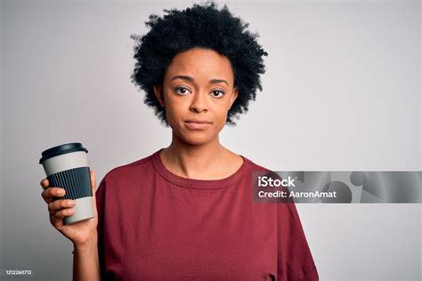 젊은 아프리카계 미국인 아프로 여자 와 곱슬 머리 마시는 컵 의 커피 와 자신감 표정에 스마트 얼굴 생각 심각한 감정에 대한 스톡 사진 및 기타 이미지 Istock