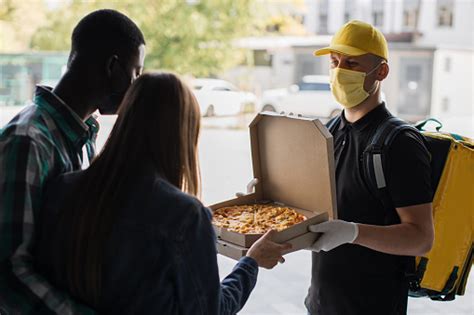 노란색 얼굴 마스크로 스밀링 배달원 피자와 함께 골판지 상자를 배달하는 유니폼 캡 25 29세에 대한 스톡 사진 및 기타 이미지 25 29세 30 34세 가방