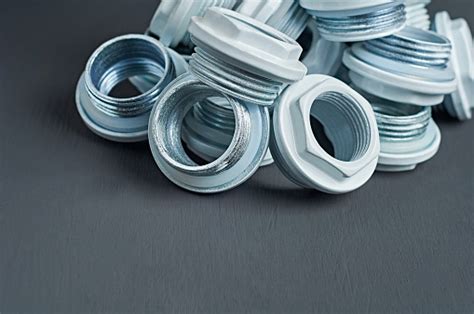 열 실용 바이메탈 또는 알루미늄 라디에이터용 이중 실이 있는 많은 새로운 흰색 너트 더미는 작업장의 어두운 콘크리트 테이블에 놓여 있습니다 클로즈업 텍스트의 공백입니다