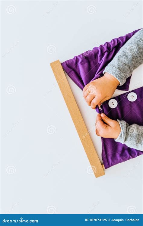 Girl Buttoning A Montessori Frame To Develop The Dexterity Of Her