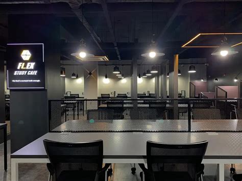 심플한 블랙톤 바탕에 노출 천장과 넓은 중앙 테이블에 철제 가림막 팬던트 조명과 기둥에 화이트 블랙 조합의 로고 브랜딩이 인상적인 스터디 카페 공유 학습 공간 사진