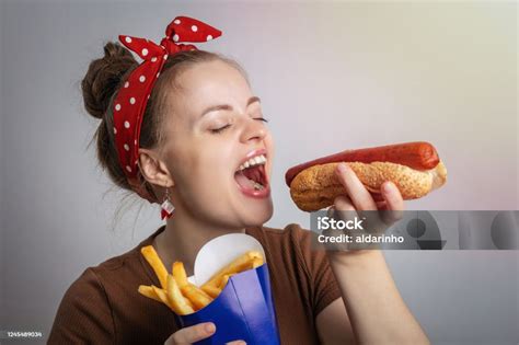젊은 백인 여자 여자 들고 먹는 큰 크기의 핫도그 롤빵과 감자 튀김 건강에 해로운 패스트 푸드 개념 핫도그에 대한 스톡 사진 및