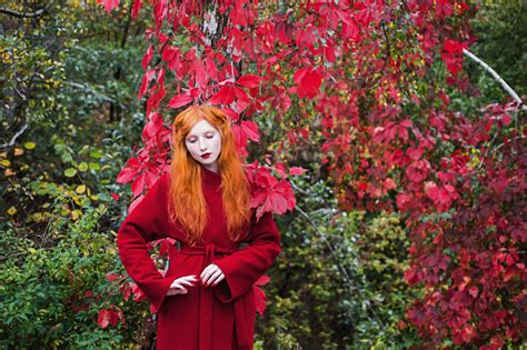 밝은을 바탕에 빨간 코트에 붉은 스트레이트 머리를 가진 여자 창백한 피부와 파란 눈과 손가락 및 빨간 손톱에 반지와 함께 밝은 특이 한 외관을 가진 빨간 머리 소녀 스트리트