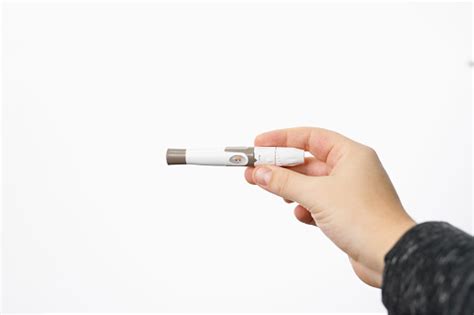 하얀 배경에 포도당 측정기로 혈당 수치를 검사하기 위한 랜싯을 들고 있는 남자의 손 당뇨병 모니터링 개념 사람들에 대한 스톡