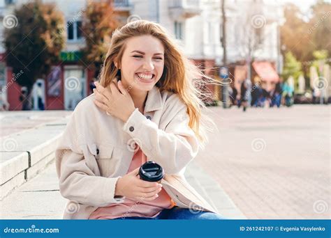 Student Sitting On The Steps With A Cup Of Coffee And Laughing Out Loud