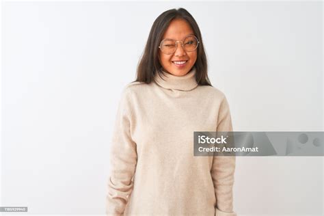 거북이 스웨터와 안경을 착용한 젊은 중국 여성이 섹시한 표정과 명랑하고 행복한 얼굴로 카메라를 바라보고 있는 고립된 흰색 배경 윙크 겨울에 대한 스톡 사진 및 기타 이미지