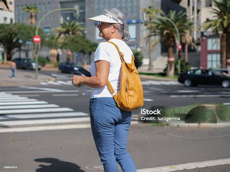 활동적인 노인 관광 여성은 캐주얼 한 옷을 입고 휴대 전화와지도를 들고 도시 거리를 건너 걷고 도시 생활을 배경으로 합니다 70 79세에 대한 스톡 사진 및 기타 이미지