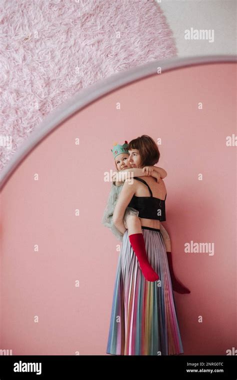 Mother Holding Her Daughter In Her Arms On A Pink Background Stock