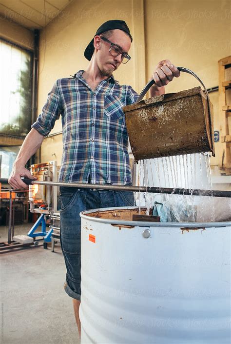 Young Glass Artist Cooling Hot Blowpipe By Stocksy Contributor