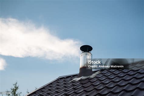 이 사진은 구름 낀 하늘을 배경으로 연기를 공기 중으로 방출하는 굴뚝이 있는 구조를 보여주며 건축 엔지니어링 및 자연 요소의 응집력 있는 혼합을 보여줍니다 0명에 대한 스톡