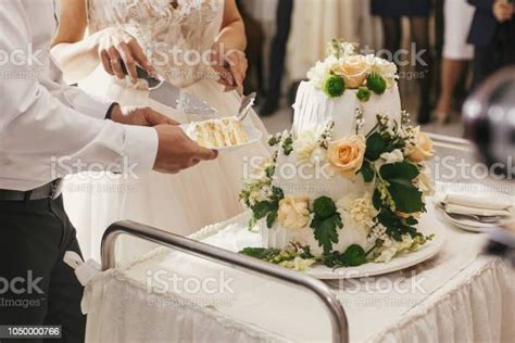 화려한 신부와 함께 절단 세련 된 신랑 웨딩 케이크 결혼식 피로연에서 장미와 화이트 행복 한 웨딩 커플 케이크 맛입니다 신혼의 로맨틱 한 순간 2명에 대한 스톡 사진 및