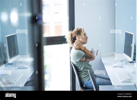 tired woman worker sitting at the desk massaging neck and shoulders for