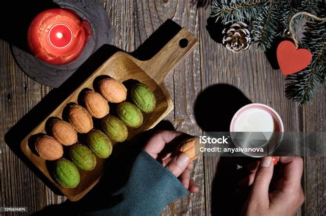 덜스 드 레체 가당 응축 우유와 호두 모양 쿠키 자연 장식어두운 나무 테이블에 창조적 인 상단보기 손에 우유 컵 전나무 나뭇 가지 마음 양초 소나무 콘 겨울에 대한 스톡