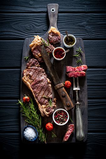 조각 스트립 스테이크 탑 로인 스테이크 쇠고기 고기 와 카버 포크 에 도마 에 검은 나무 굽기에 대한 스톡 사진 및 기타 이미지