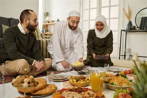 Babe Muslim Man In White Kandora And Skullcap Sitting Between His Twin Brother In Casualwear