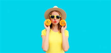 파란색 배경에 둥근 밀짚모자를 쓰고 꽃 봉오리와 공기 키스를 보내는 입술을 부는 행복한 젊은 여성의 여름 초상화 25 29세에 대한 스톡 사진 및 기타 이미지 Istock