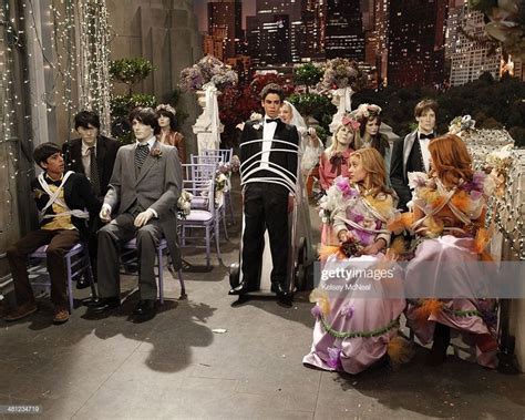 A Group Of People Standing Around Each Other In Front Of A Building With Lights On