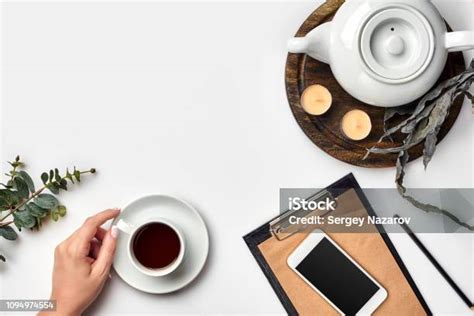 젊은 여자의 오른손 아침 시간에 차 컵 스마트폰와 주전자 옆에 흰색 테이블에 빈 노트에 작성 갈색에 대한 스톡 사진 및 기타
