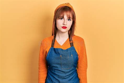 Redhead Young Woman Wearing Apron With Serious Expression On Face Stock