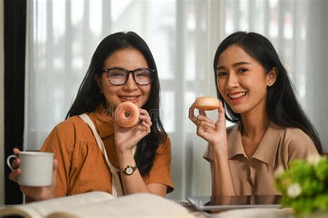 Positive Female Best Friends Eating Donuts And Enjoying Free Time