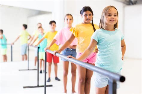 Smiling Tween Girl Practicing Classic Dance Moves Near Ballet Barre