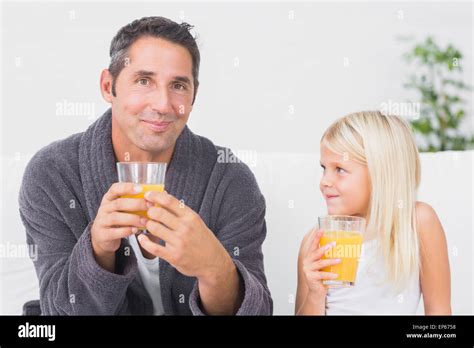 Father and daughter drinking glass of orange juice Stock Photo - Alamy