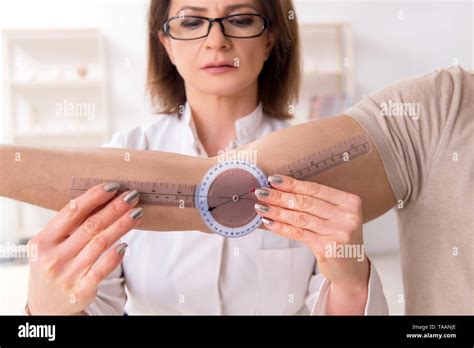 Female Doctor Checking Patients Joint Flexibility With Goniometer