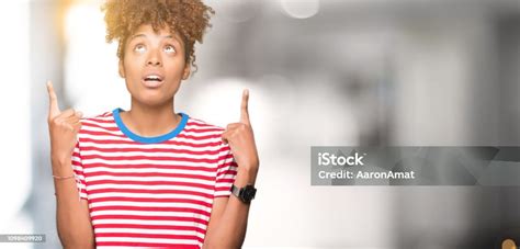 격리 된 배경 위에 아름 다운 젊은 아프리카계 미국인 여자 놀라게 했 고 올려 손가락으로 가리키는 그리고 팔 놀 랐 어 요 T