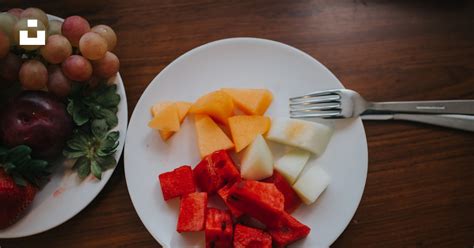 얇게 썬 수박과 망고를 포크로 접시에 담다 사진 Unsplash의 무료 음식 이미지