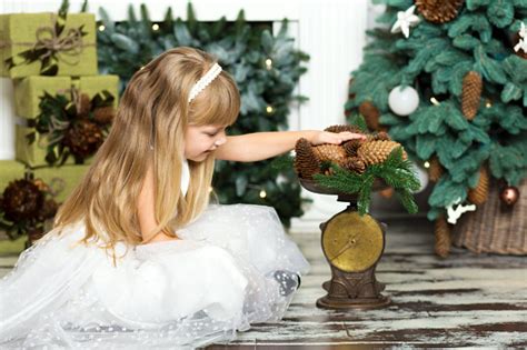 어린 소녀는 크리스마스 트리에 대한 비늘 소나무 콘 장식에 무게 메리 크리스마스와 새해 복 설 사람과 아이들 개념 12월에 대한