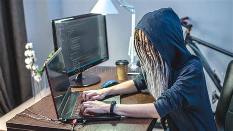 hacker in a hood are programming virus code on a laptop the concept of