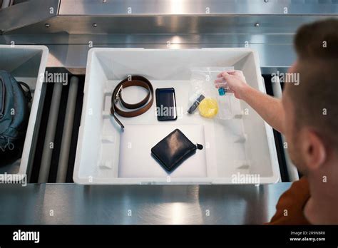 Airport Security Check Before Flight Passenger Holding Plastic Bag With Liquids Above Container