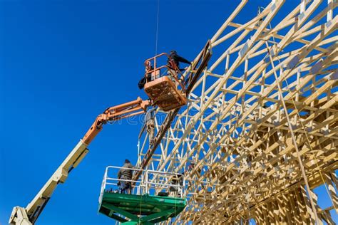 Construction Workers Assembling Wooden Structure On Clear Day In Bustling Urban Area Stock Image