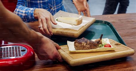 튀긴 야채와 치즈 케이크를 곁들인 육즙이 많은 구운 스테이크를 나무 책상에서 고객이나 웨이터에게 제공합니다 쇼핑몰 컨셉의 푸드 코트에서 케이터링 텍스트 공간 현대적인