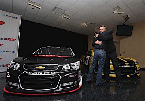 Two Men Hugging Each Other In Front Of Some Racing Cars And Televisions