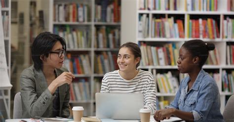 테이블에 앉아 노트북을 사용하여 팀워크에 대해 토론하고 도서관에서 커피를 마시는 학생들 사진 Unsplash의 책 이미지