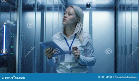female technician works on a tablet in a data center stock image
