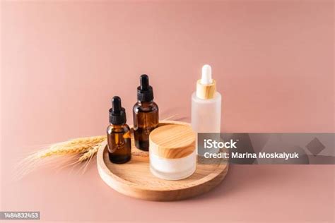 유기농 천연 요법이 담긴 스포이드와 나무 원형 쟁반과 베이지색 배경에 크림 한 병이 있는 세 가지 화장품 병 갈색에 대한 스톡 사진 및 기타 이미지 Istock
