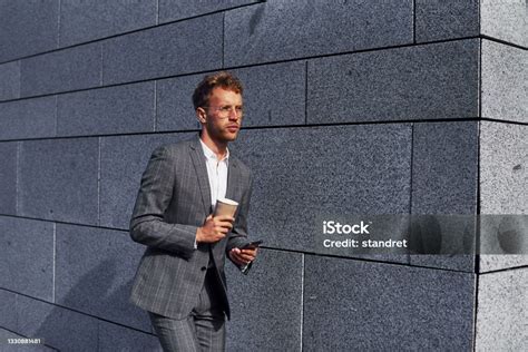 휴대 전화와 손에 음료 회색 정장 입고젊은 성공적인 사업가는 도시에서 야외입니다 20 29세에 대한 스톡 사진 및 기타 이미지