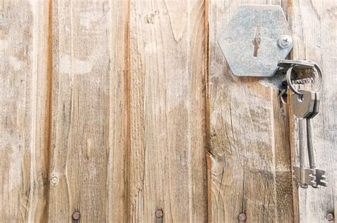 낡고 금이 가졌고 풍화되고 녹슨 손톱과 깨진 금속 얼굴이있는 나무 문 하나의 철 열쇠가 열쇠 구멍에 삽입되고 다른 두 개의