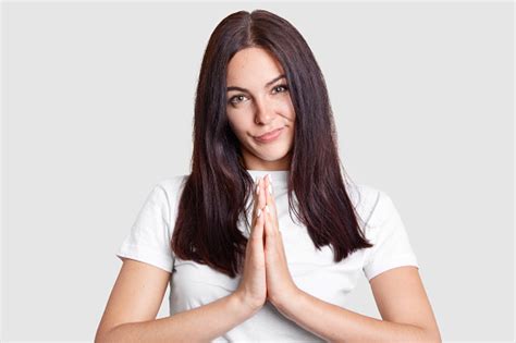 심각한 충실 한 사진 갈색 머리 여자 손바닥 함께 누르면 뭔가 대 한 기도 입은 캐주얼 T 셔츠 흰색 배경 위에 절연 용 묻습니다 신체 언어 갈색 머리에 대한 스톡 사진 및