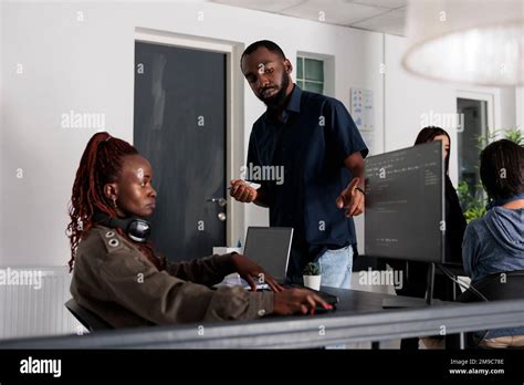 African American Software Developers Discussing About Coding Script In Front Of Computer
