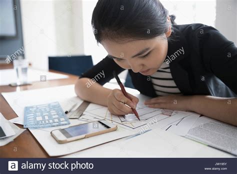 Dedicated Female Architect Drafting Blueprints In Conference Room Stock