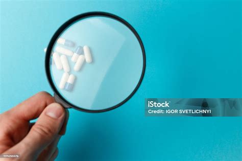 파란색 배경에 돋보기 아래 제약 의약품 알약 정제 및 캡슐을 모듬 맨 위 보기 플랫 레이 공간을 복사합니다 의학 개념 파스텔 배경에 알 약의 힙 0명에 대한 스톡 사진 및