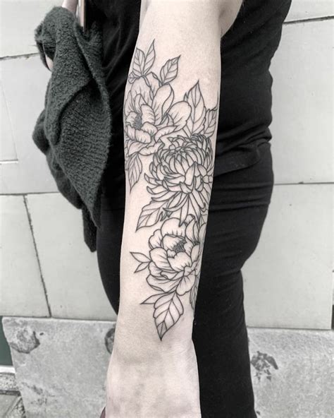 A Black And White Photo Of A Womans Arm With Flowers Tattooed On It