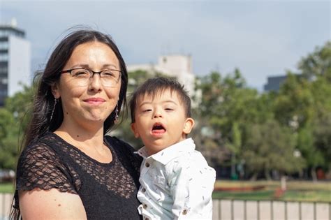 Premium Photo Portrait Of Mother And Her Son With Down Syndrome Looking At Camera In A Park